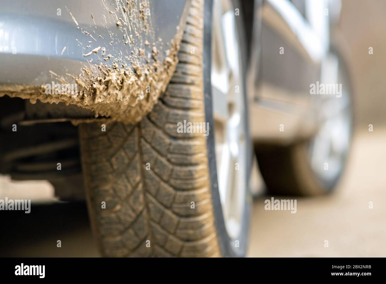 Close up of dirty car wheel with rubber tire covered with yellow mud ...