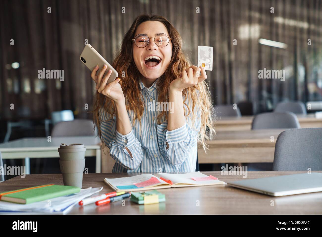 Image of excited charming woman showing credit card and mobile phone ...