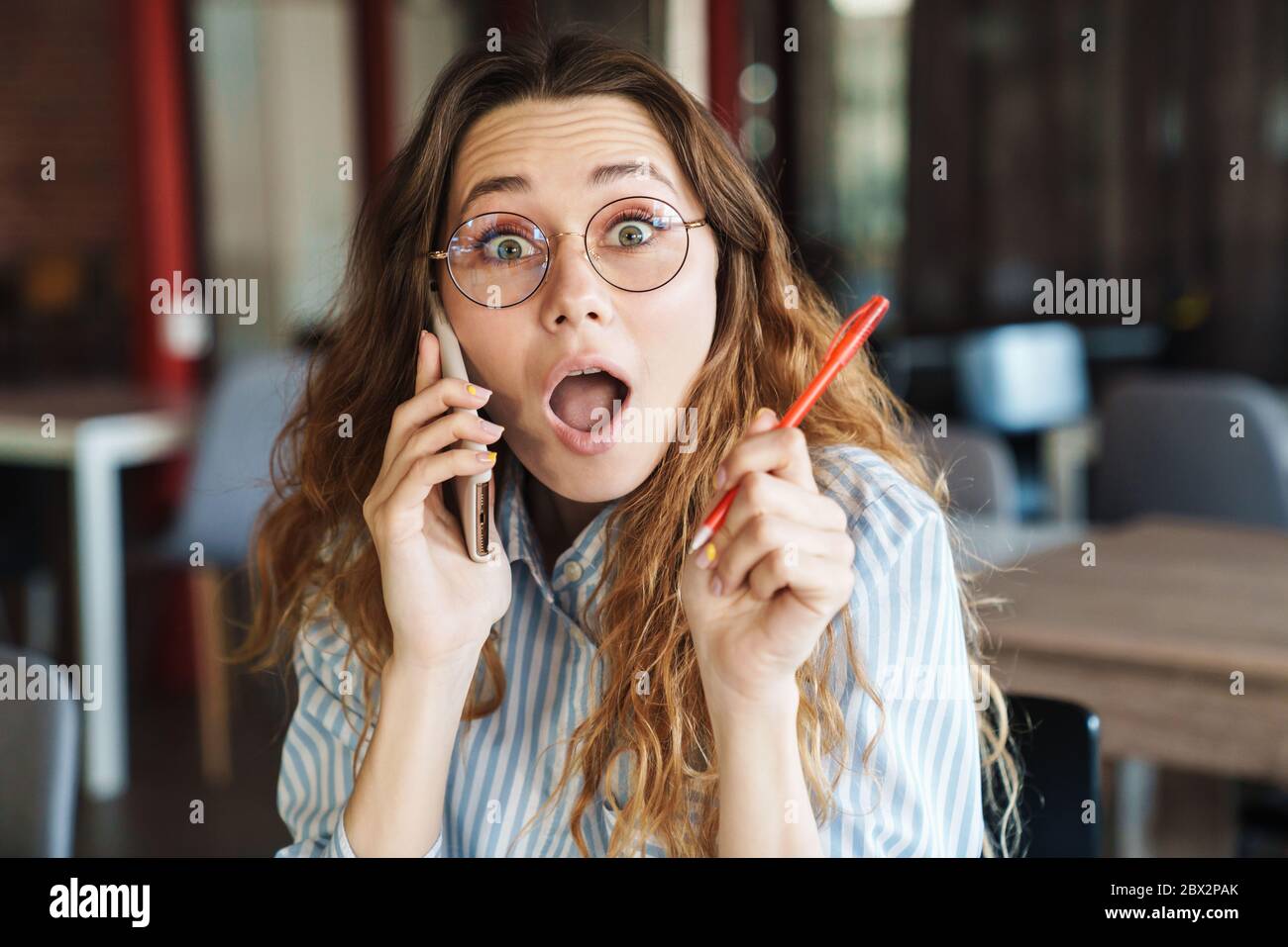 Image of shocked charming woman talking on cellphone and expressing ...