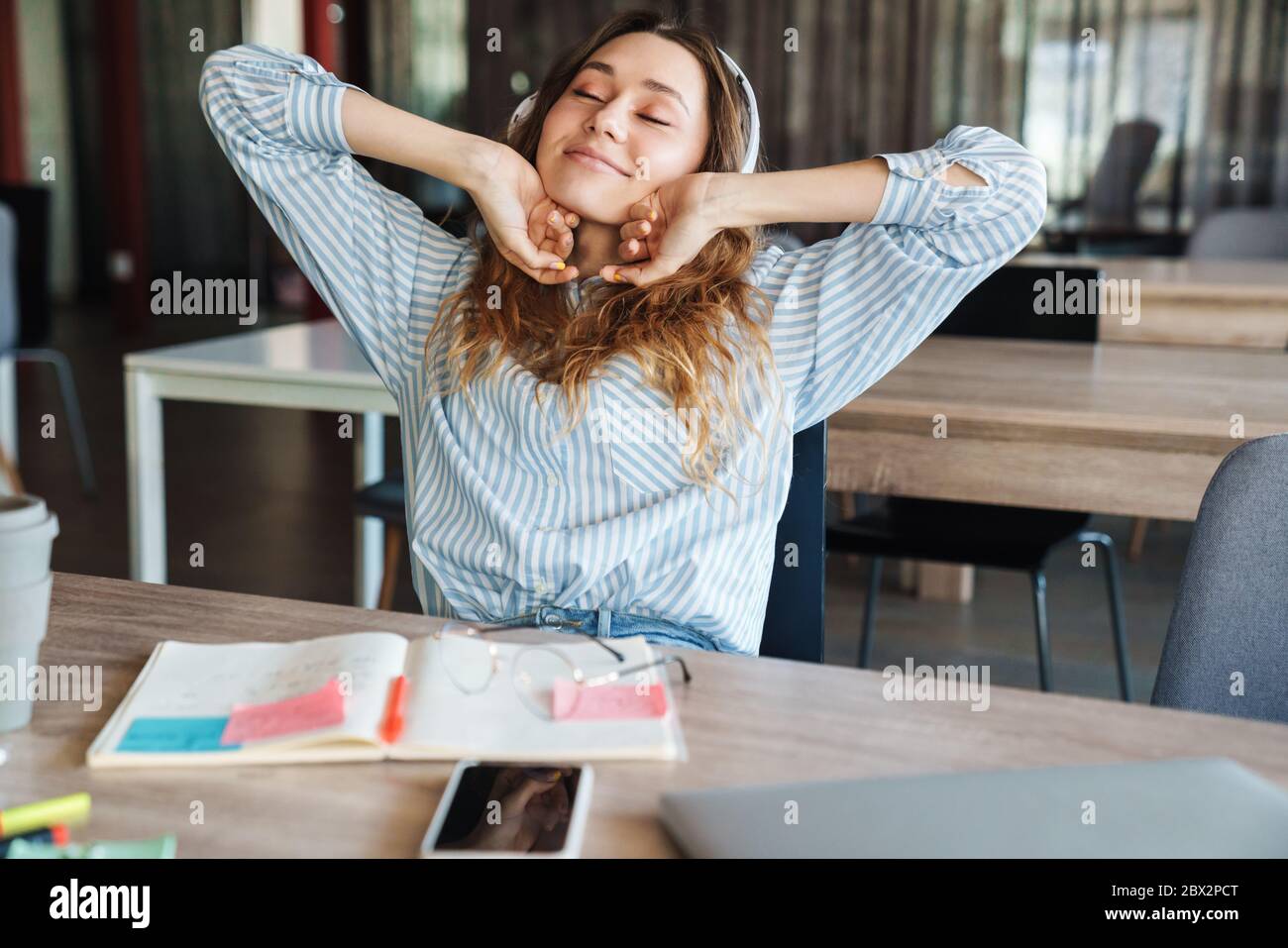 Image of relaxed young woman using headphones and stretching her body ...