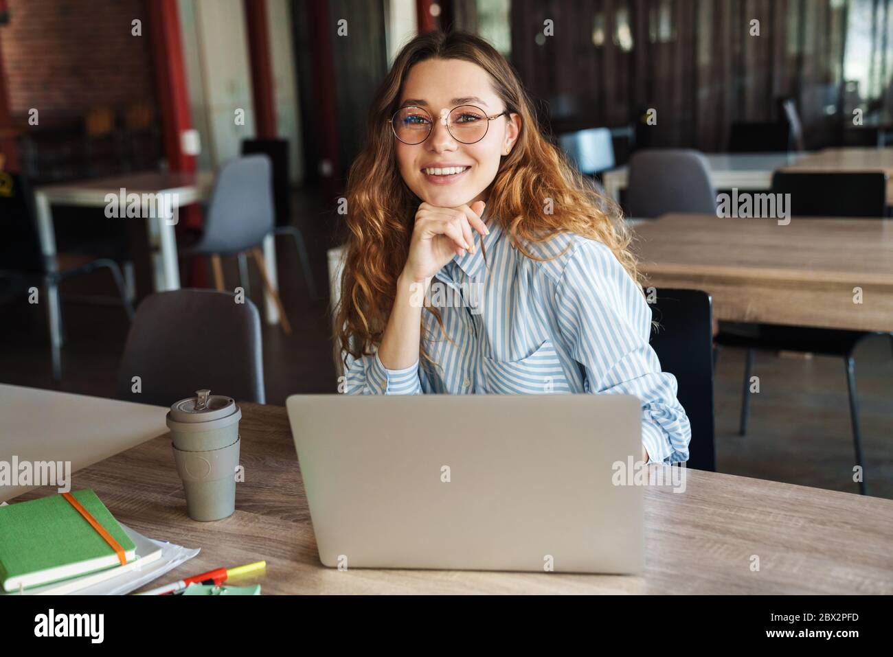 Image of happy beautiful woman using laptop and smiling while studying ...