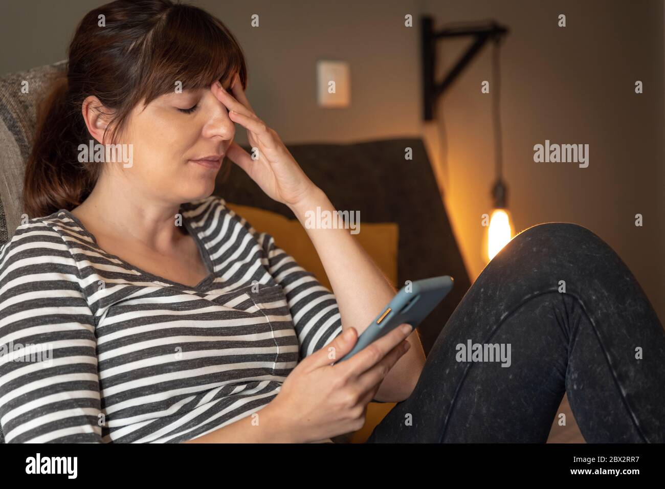 Woman on bed at phone with symptoms of depression Stock Photo - Alamy