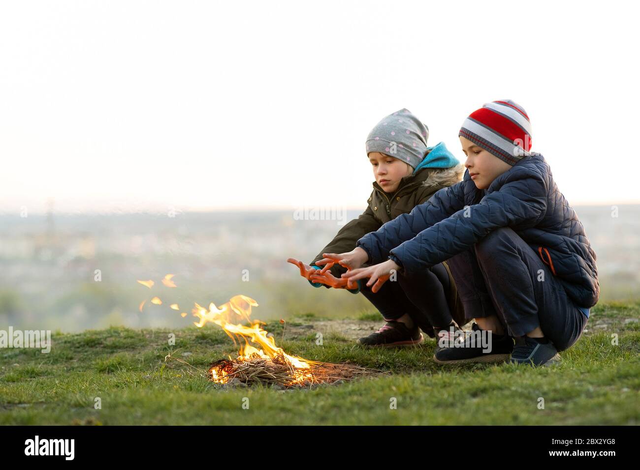 Two children playing with fire outdoors in cold weather Stock Photo - Alamy