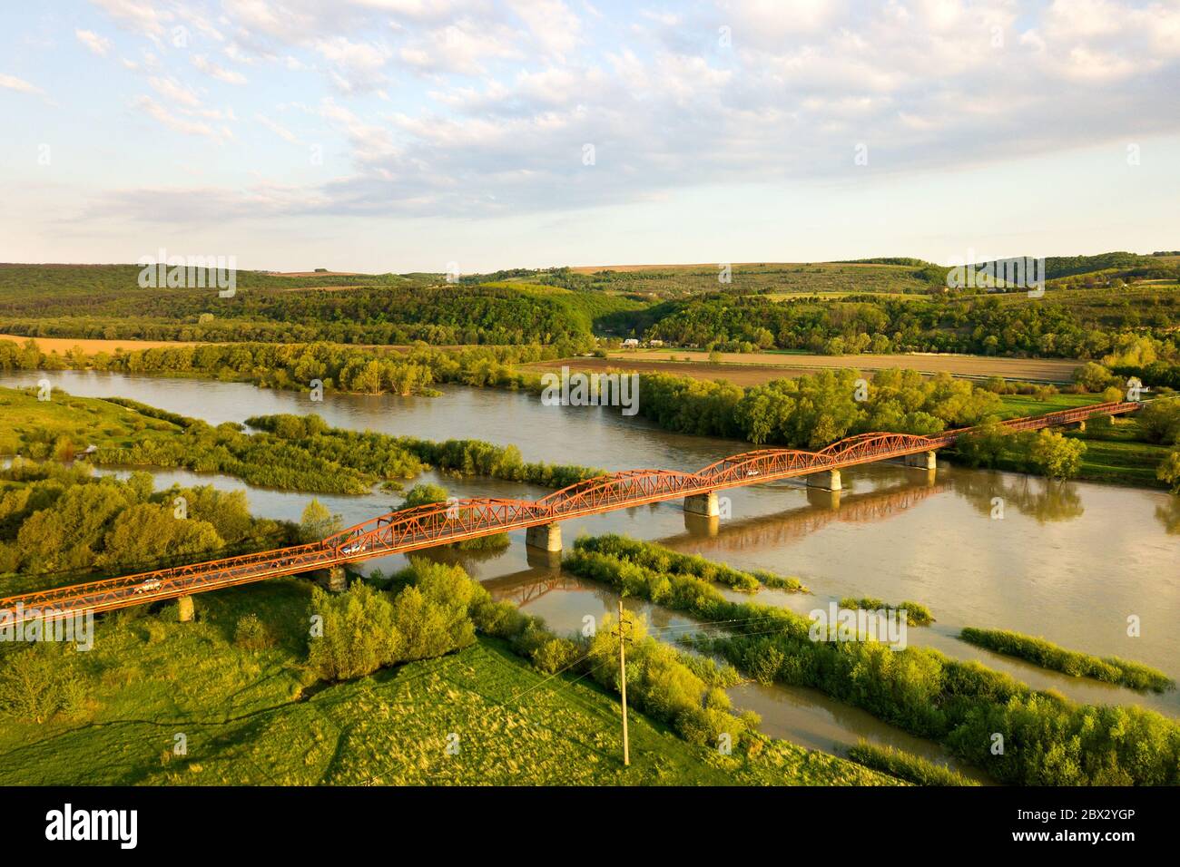 Aerial view of a narrow road bridge stretching over muddy wide river in ...