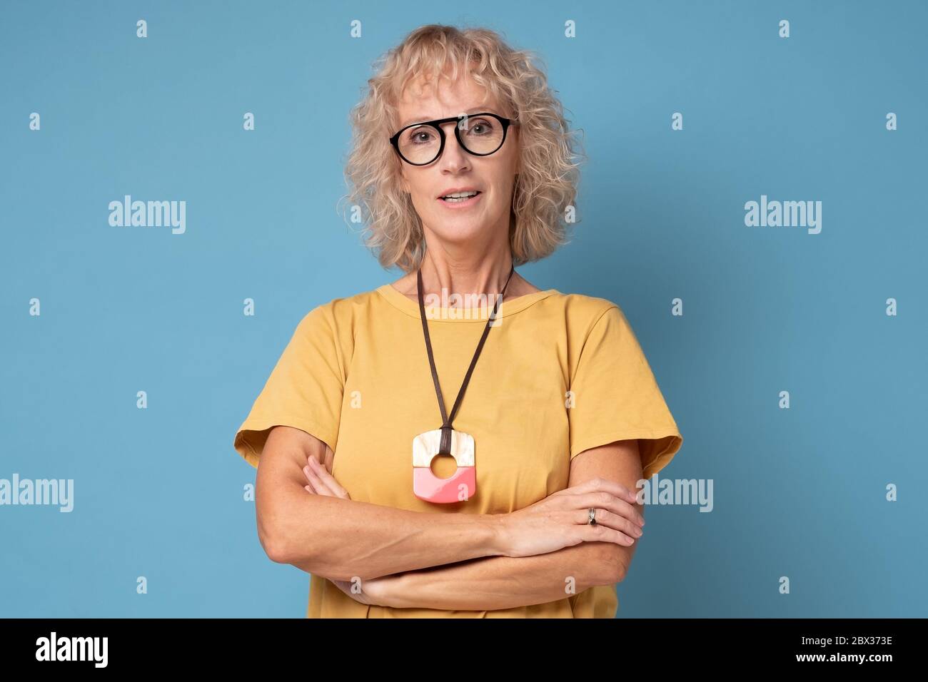 Smiling senior woman in front of blue background Stock Photo - Alamy