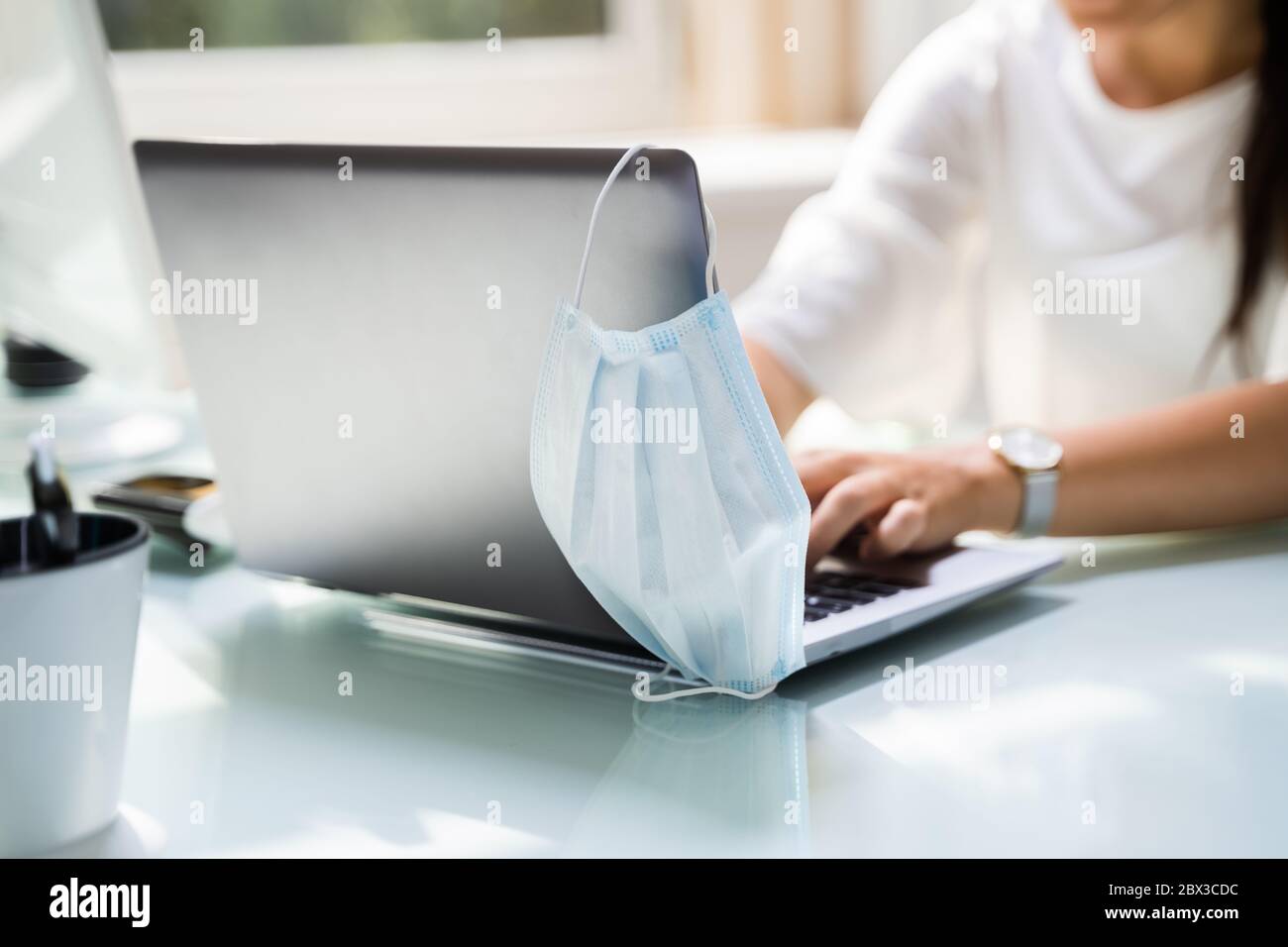 Face Mask Hanging On Laptop At Work Stock Photo - Alamy