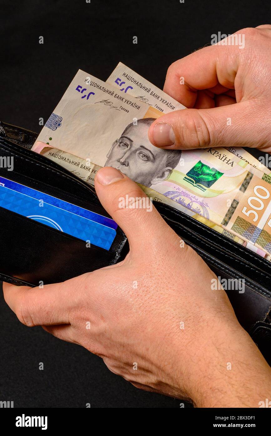 Closeup in the hands of a man's wallet when he pulls out a 500 hryvnia ...
