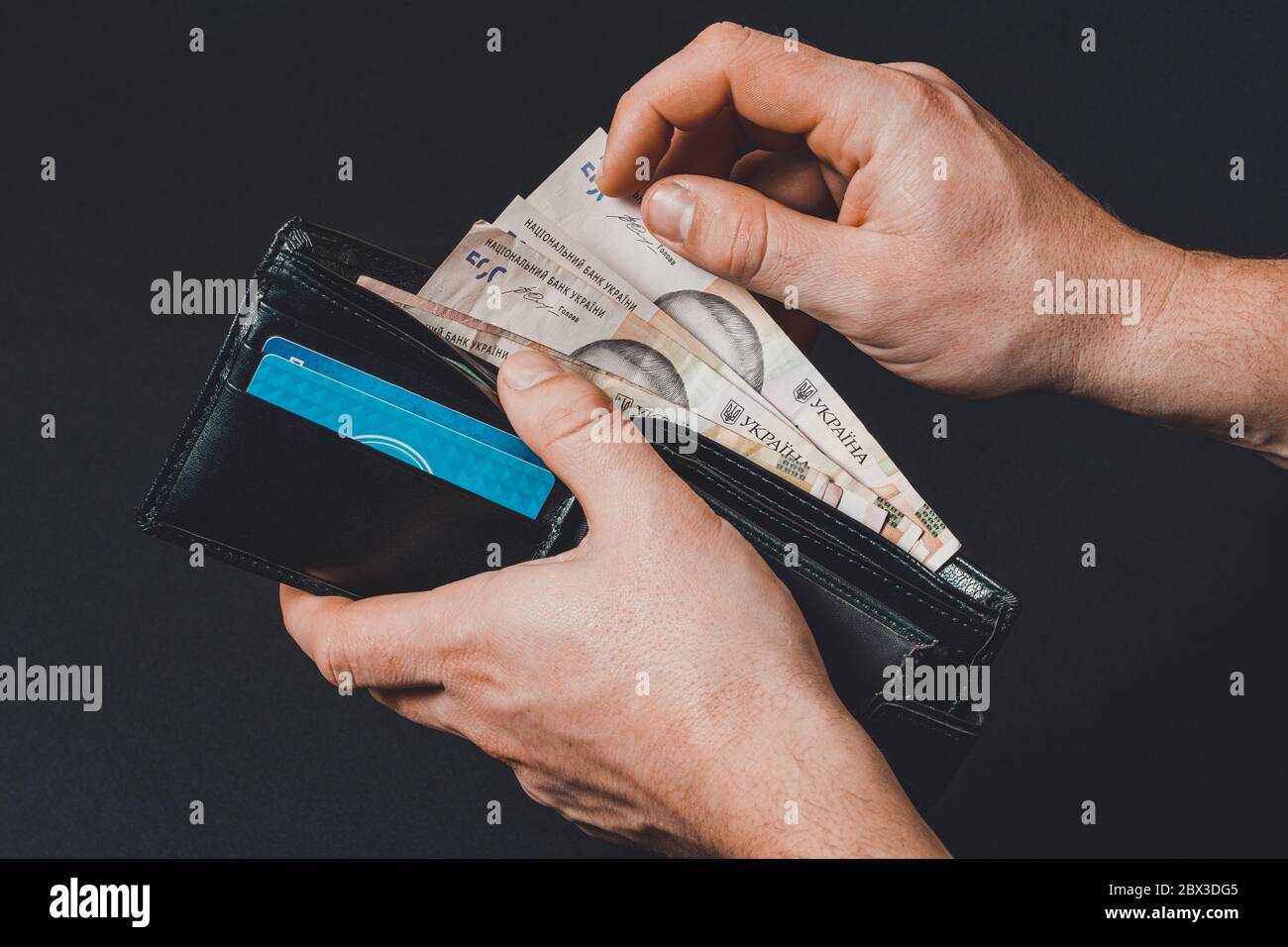 Closeup in the hands of a man's wallet when he pulls out a 500 hryvnia ...