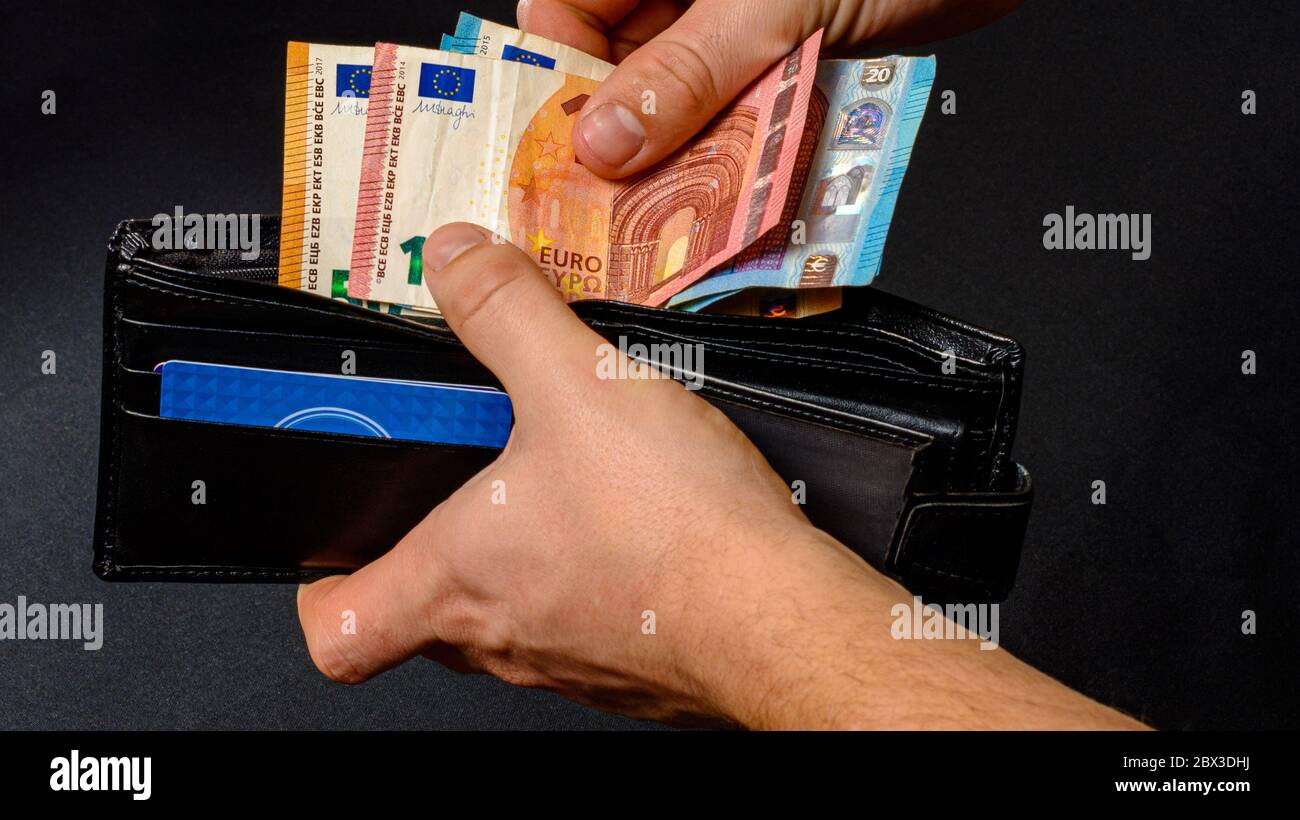 Man hand pulling money from wallet, black background and black wallet ...
