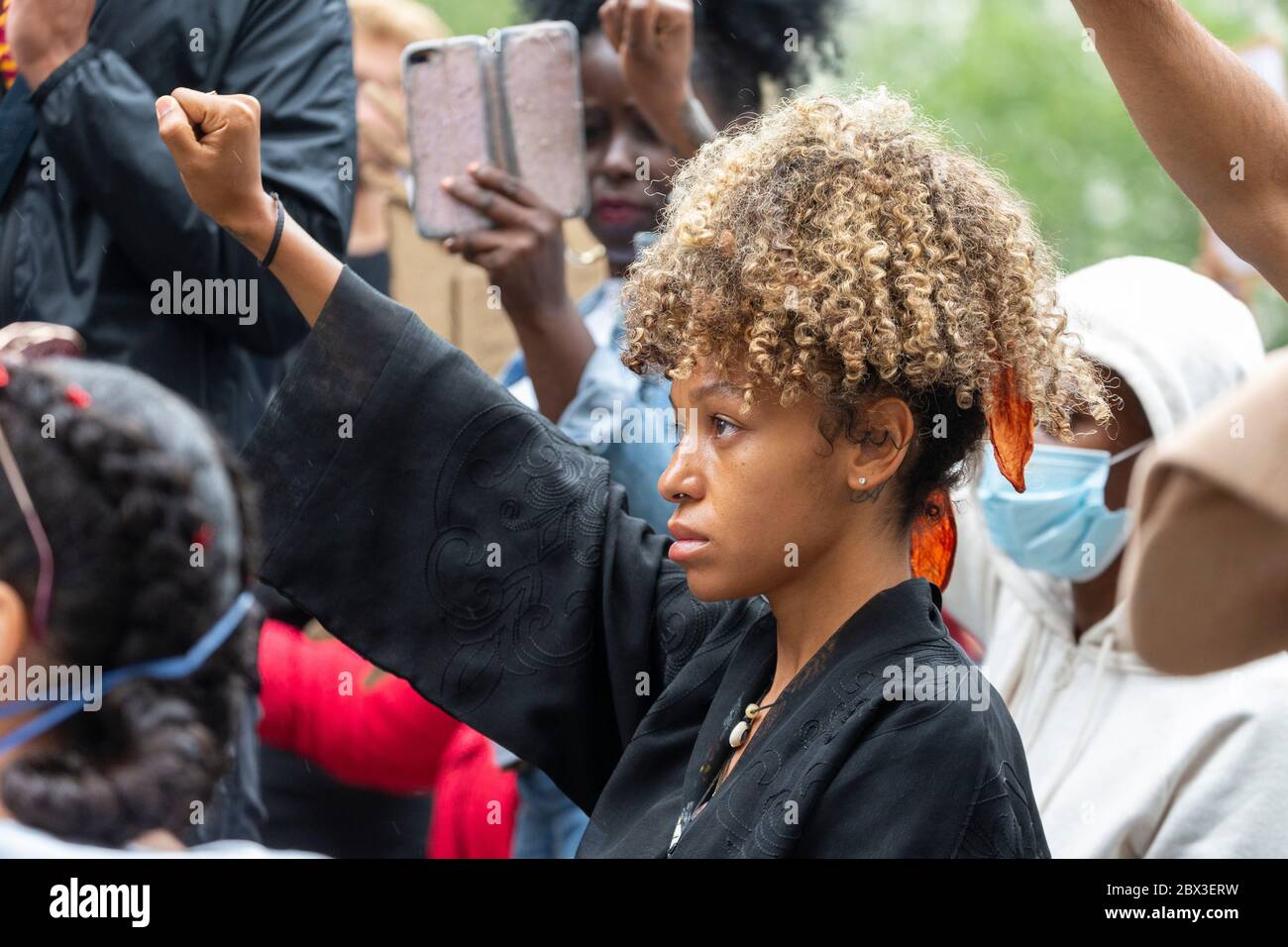 A young woman taking the knee and raising her fist during the Black ...