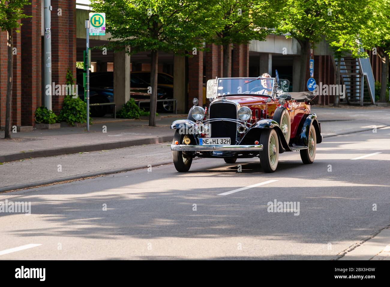 An open classic car drives past a bus stop. Oldtimer on the road in ...