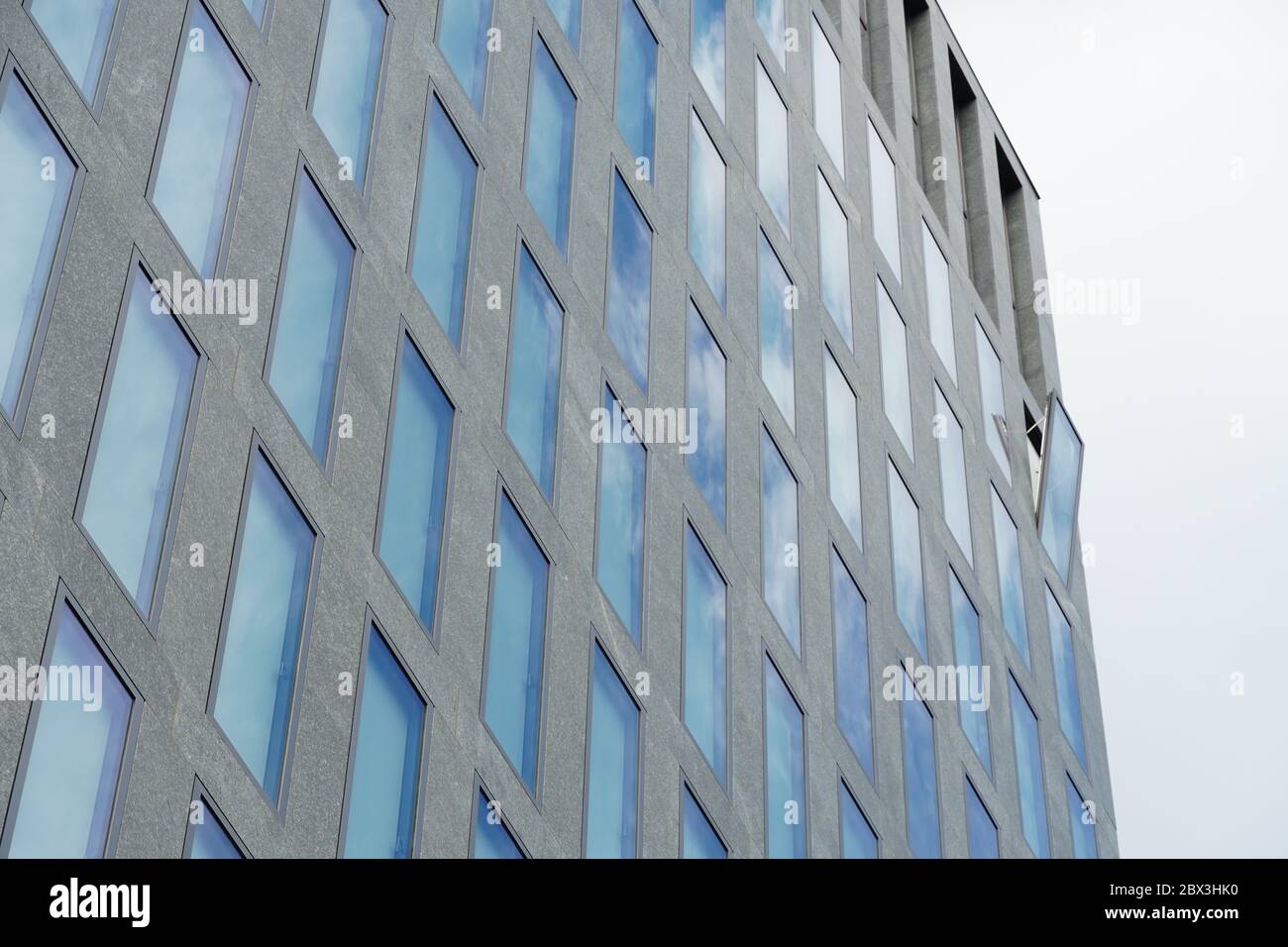 A single open window bulging out of uniform facade of an office ...