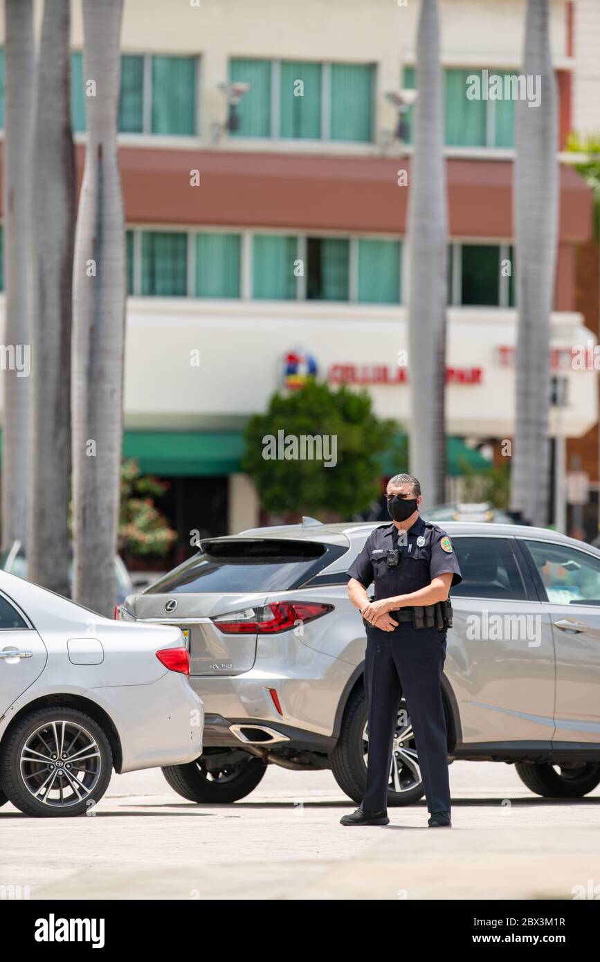 Miami Dade police officer wears a face mask as he stands guard over ...