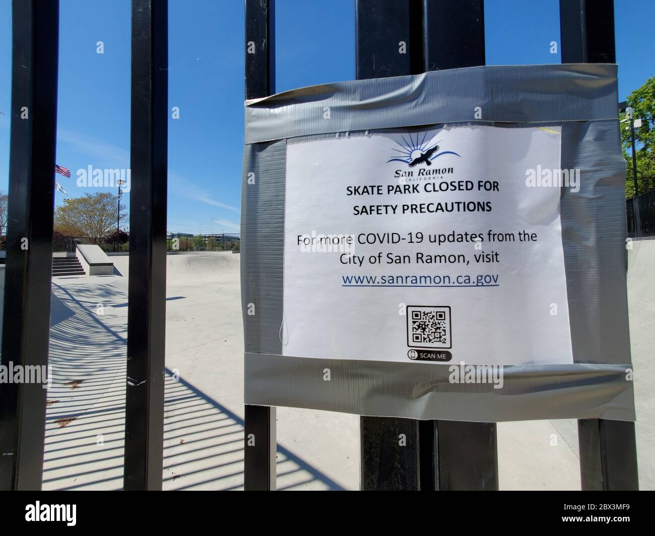 A closed municipal skate park is visible through a fence with a sign ...