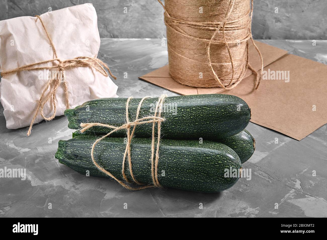 A bunch of zucchini on a gray background with a paper bag for delivery ...
