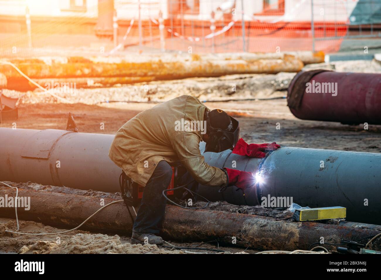 Repairing of city water supply or sewer pipeline. Worker is welding ...