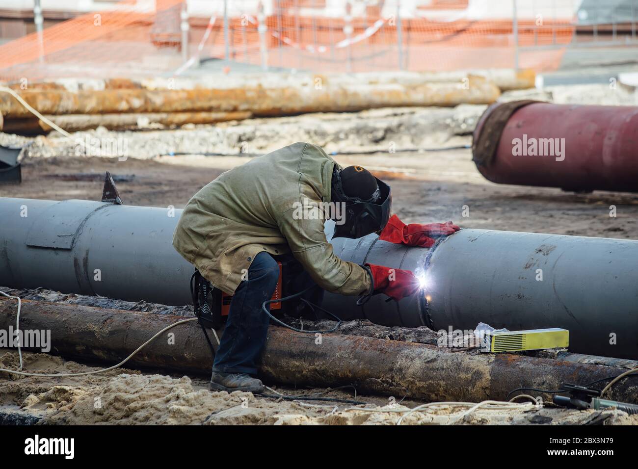 Repairing of city water supply or sewer pipeline. Worker is welding ...