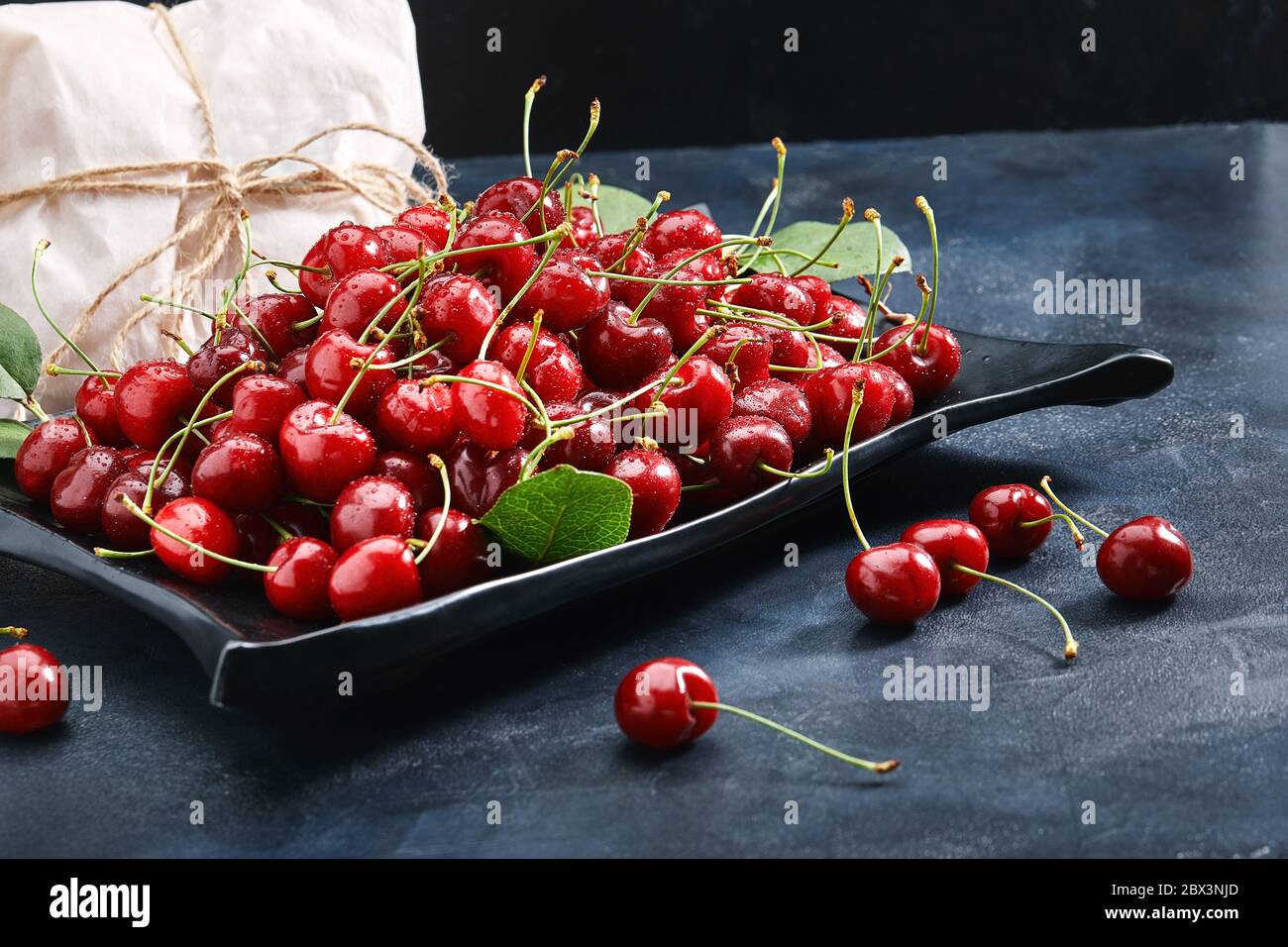 Fresh sweet cherries on a plate on a blue background. Concept of fresh ...