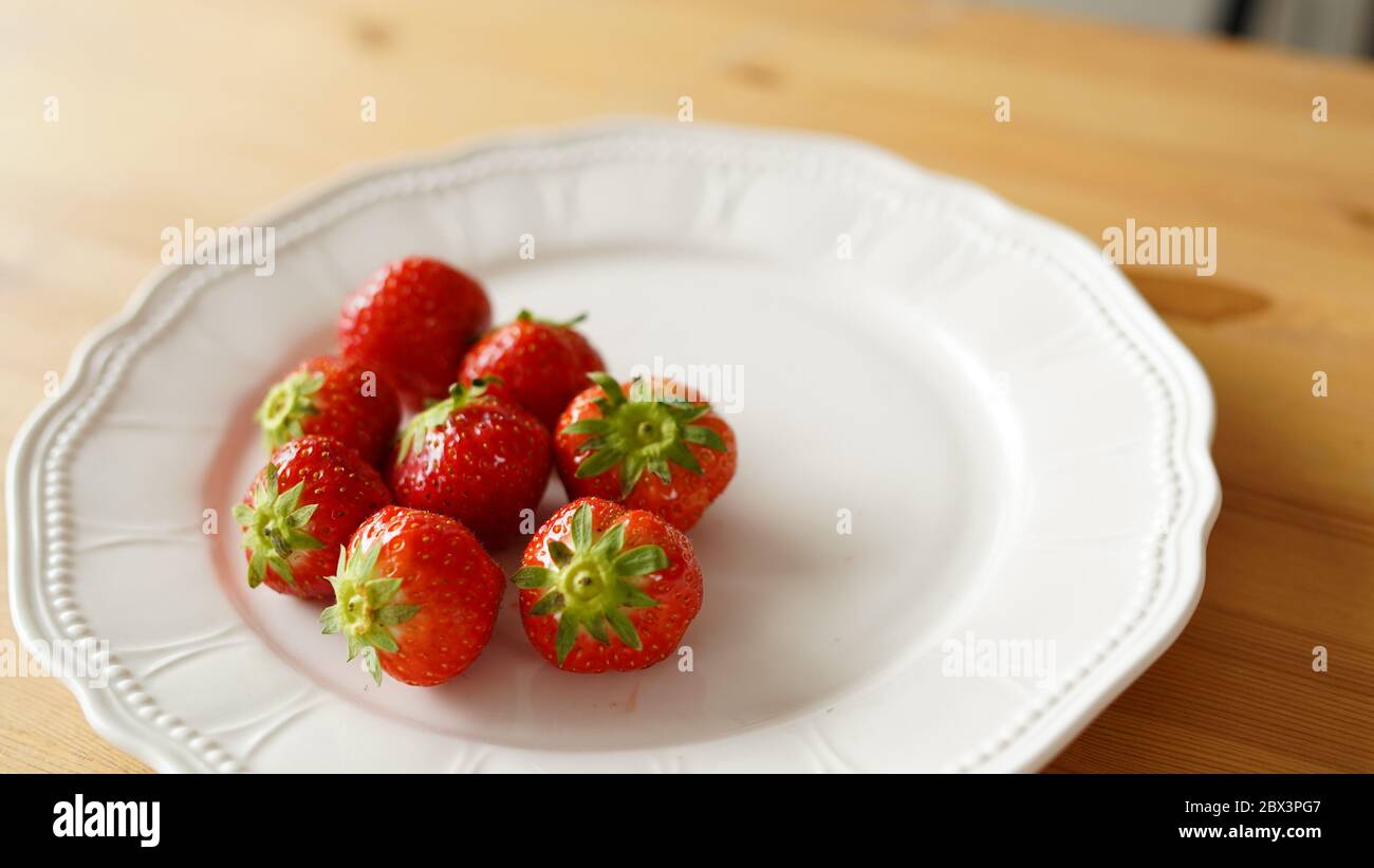 Close up of ripe strawberries on plate on table in kitchen Stock Photo ...