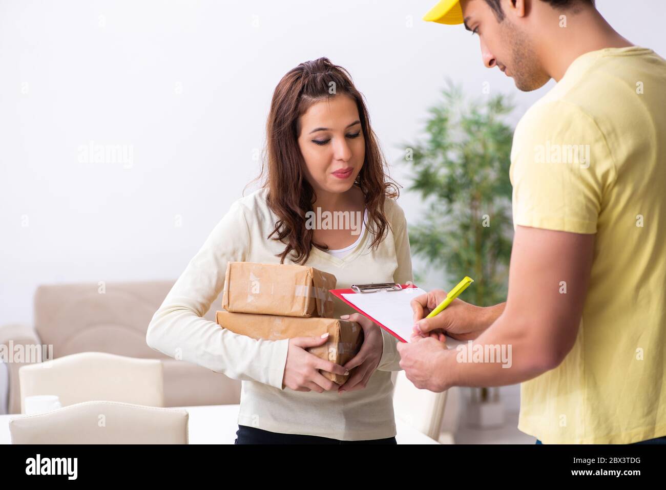 Young courier delivering parcel to the office Stock Photo - Alamy