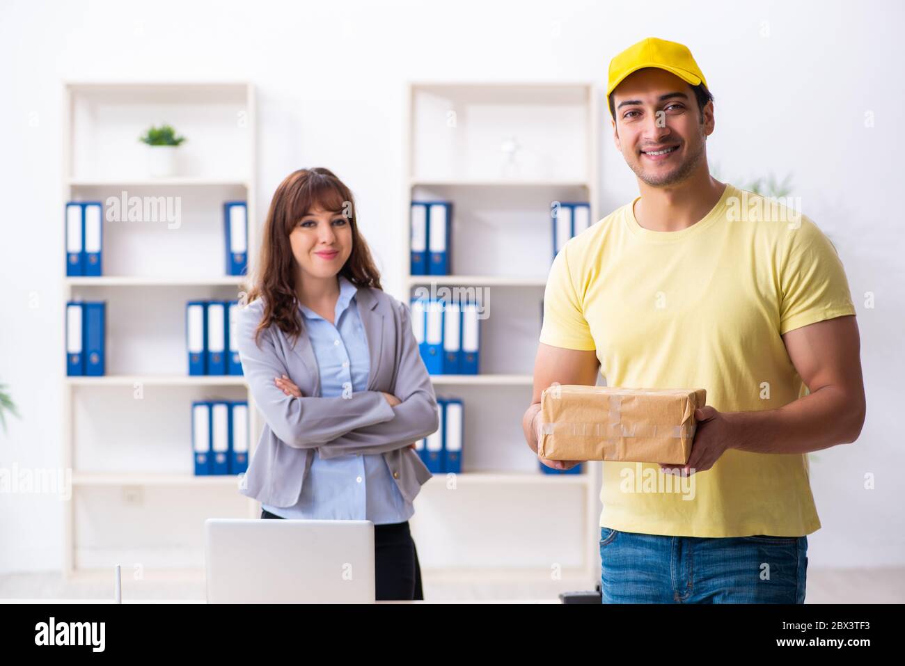 Young courier delivering parcel to the office Stock Photo - Alamy