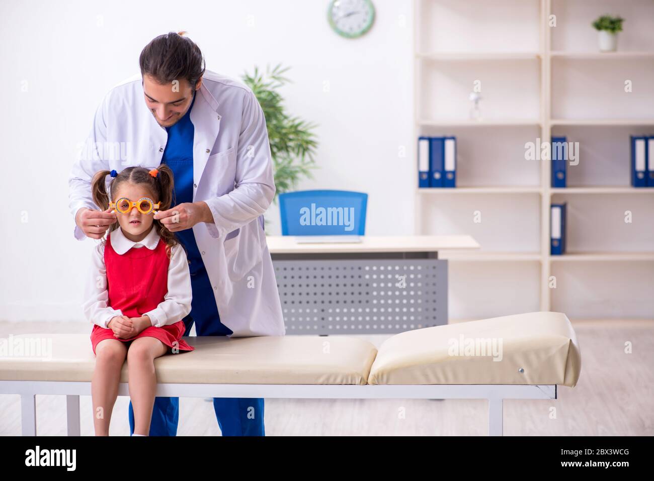 Small girl visiting young doctor oculist Stock Photo - Alamy