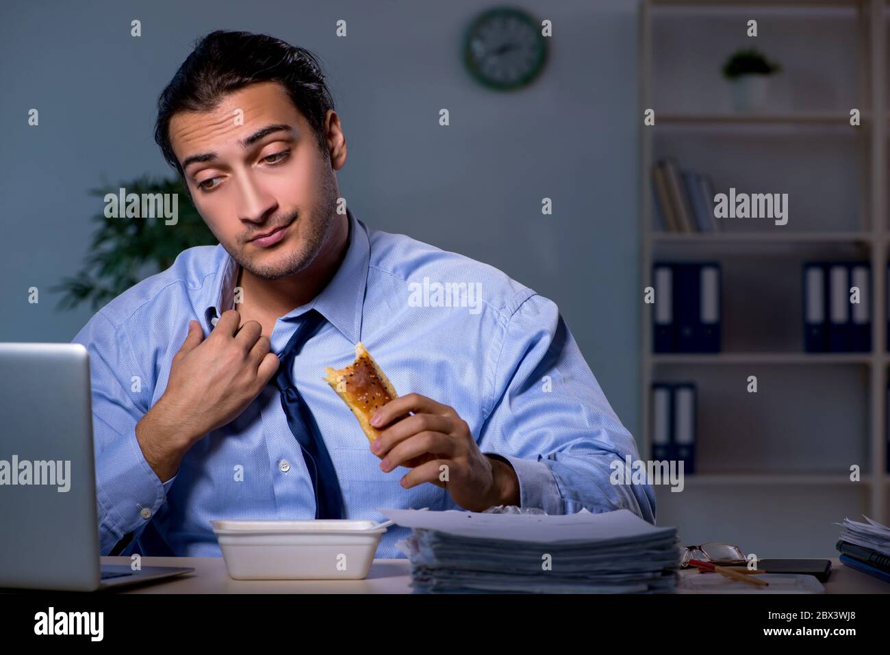 Hungry employee working late in office Stock Photo - Alamy