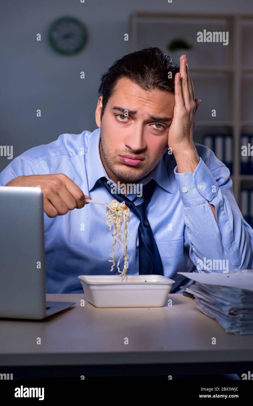 Hungry employee working late in office Stock Photo - Alamy