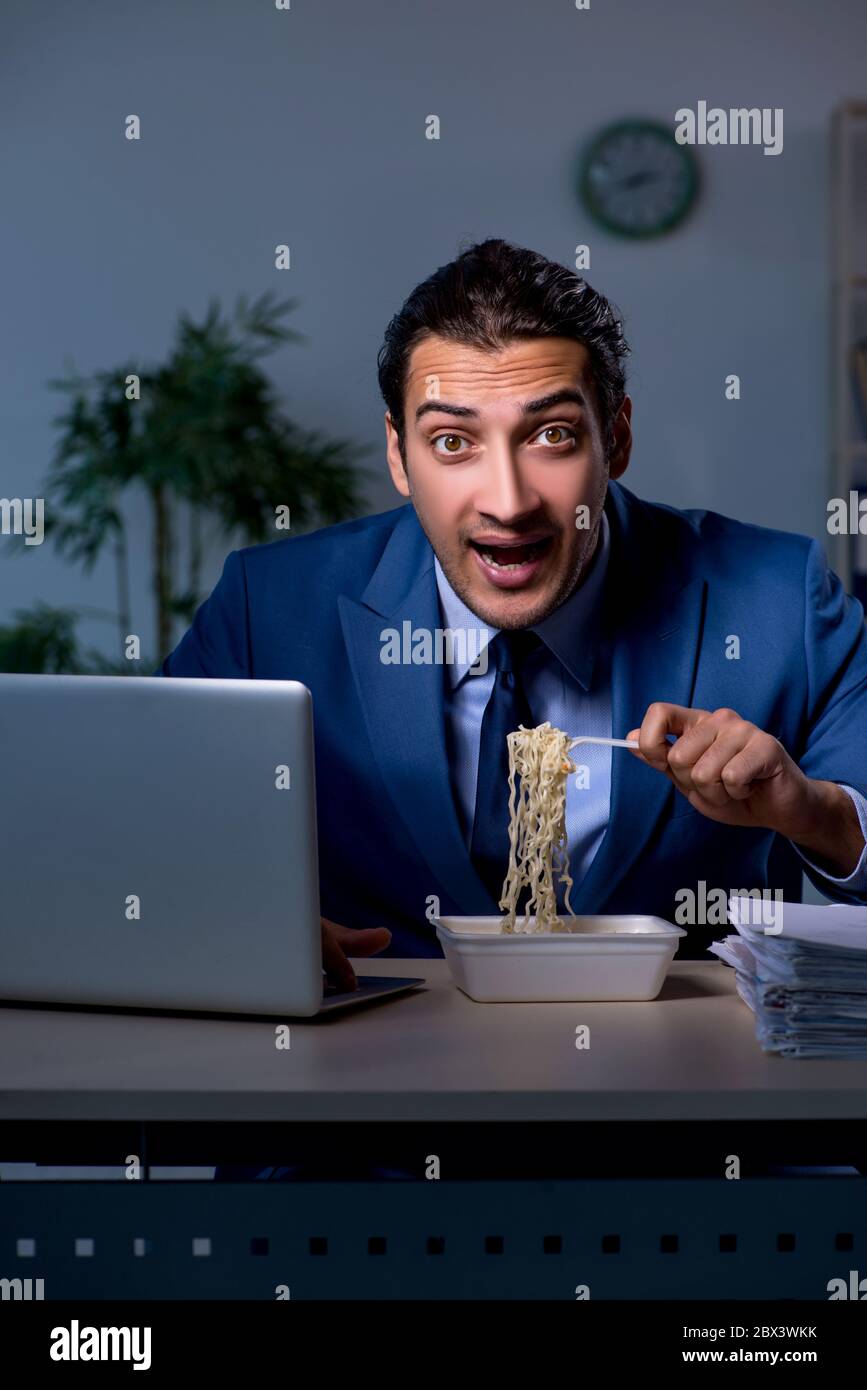 Hungry employee working late in office Stock Photo - Alamy