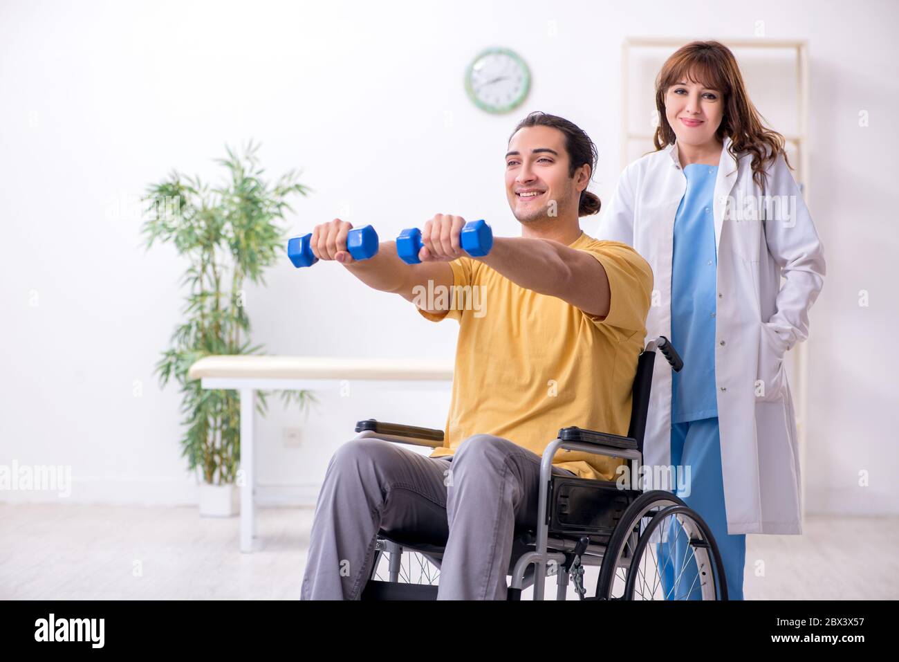 Young male patient in wheel-chair doing physical exercises in hospital ...