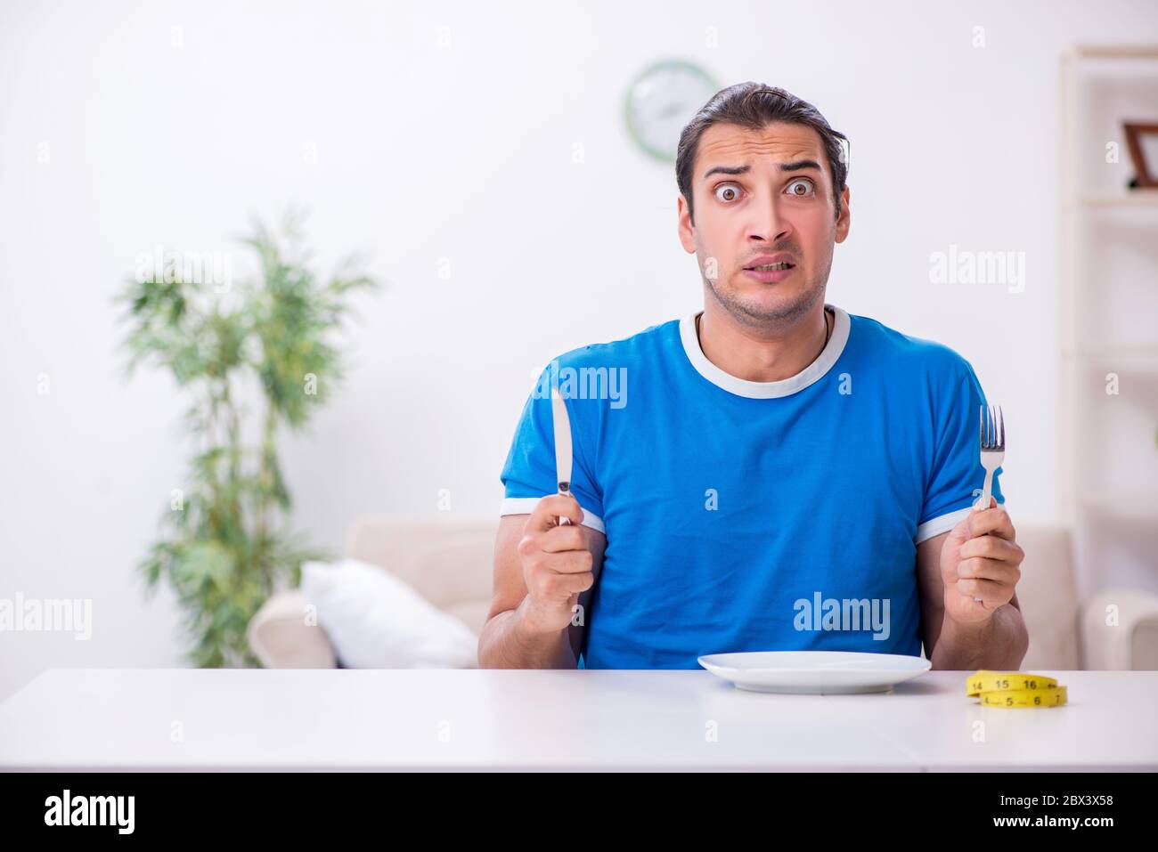Young hungry man in the dieting concept Stock Photo - Alamy