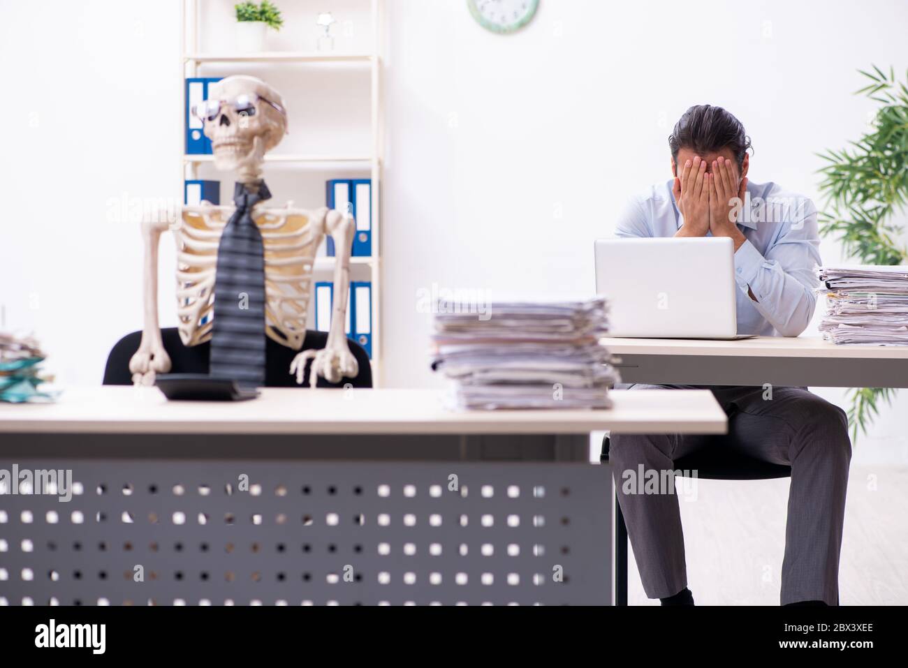 Young employee and skeleton in the office Stock Photo - Alamy