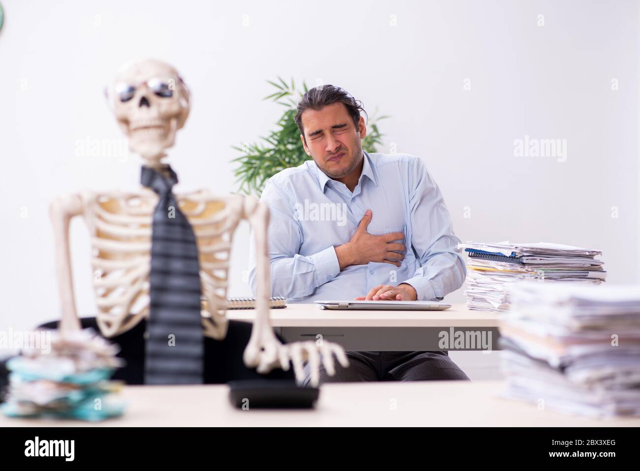 Young employee and skeleton in the office Stock Photo - Alamy