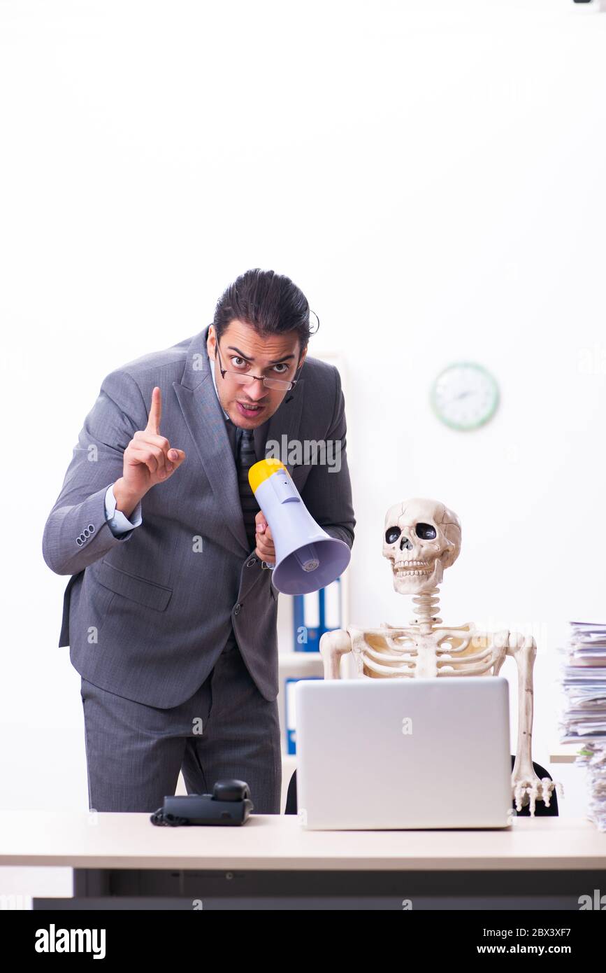 Young employee and skeleton in the office Stock Photo - Alamy
