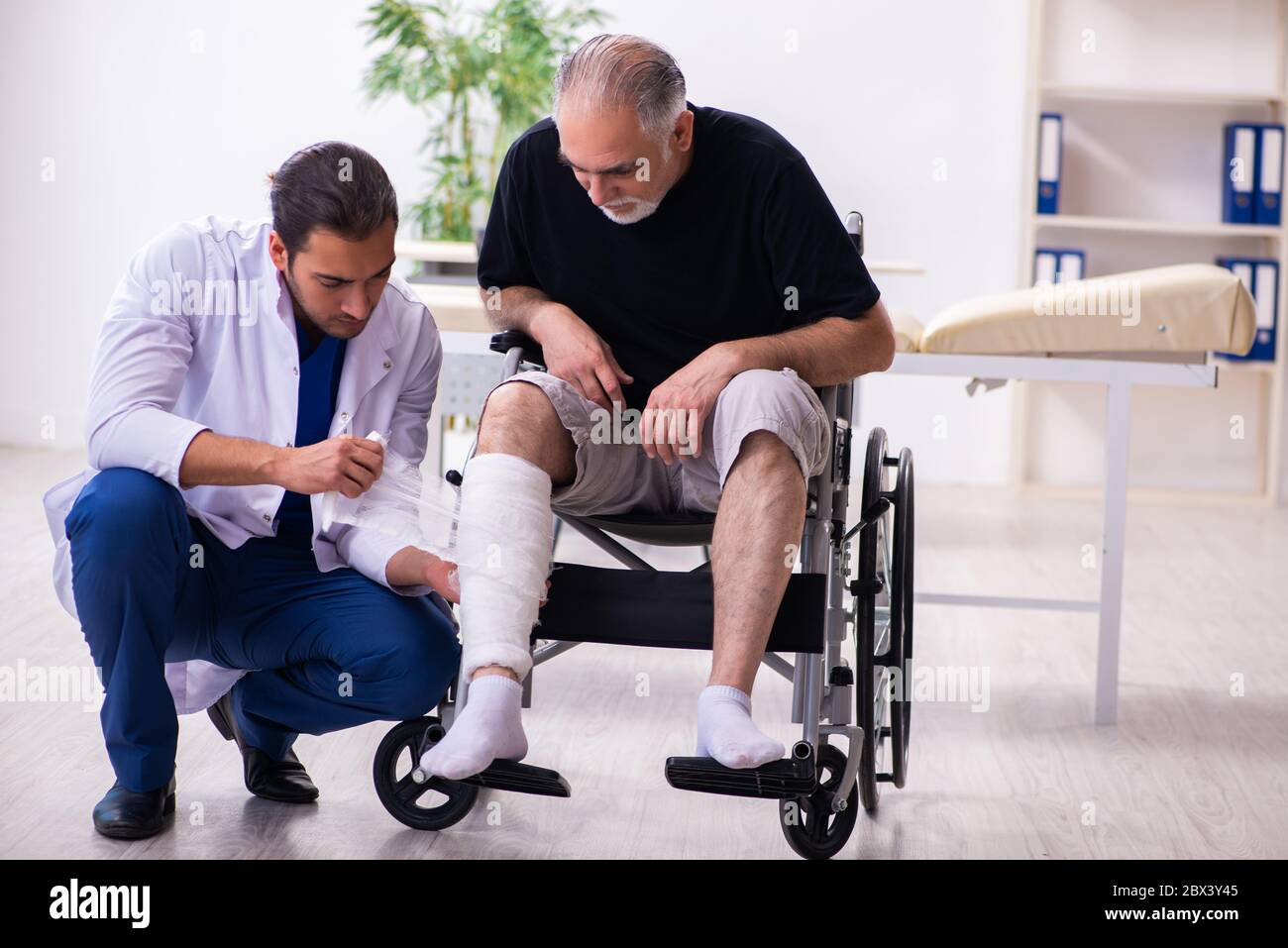 Old injured man visiting young doctor traumatologist Stock Photo - Alamy