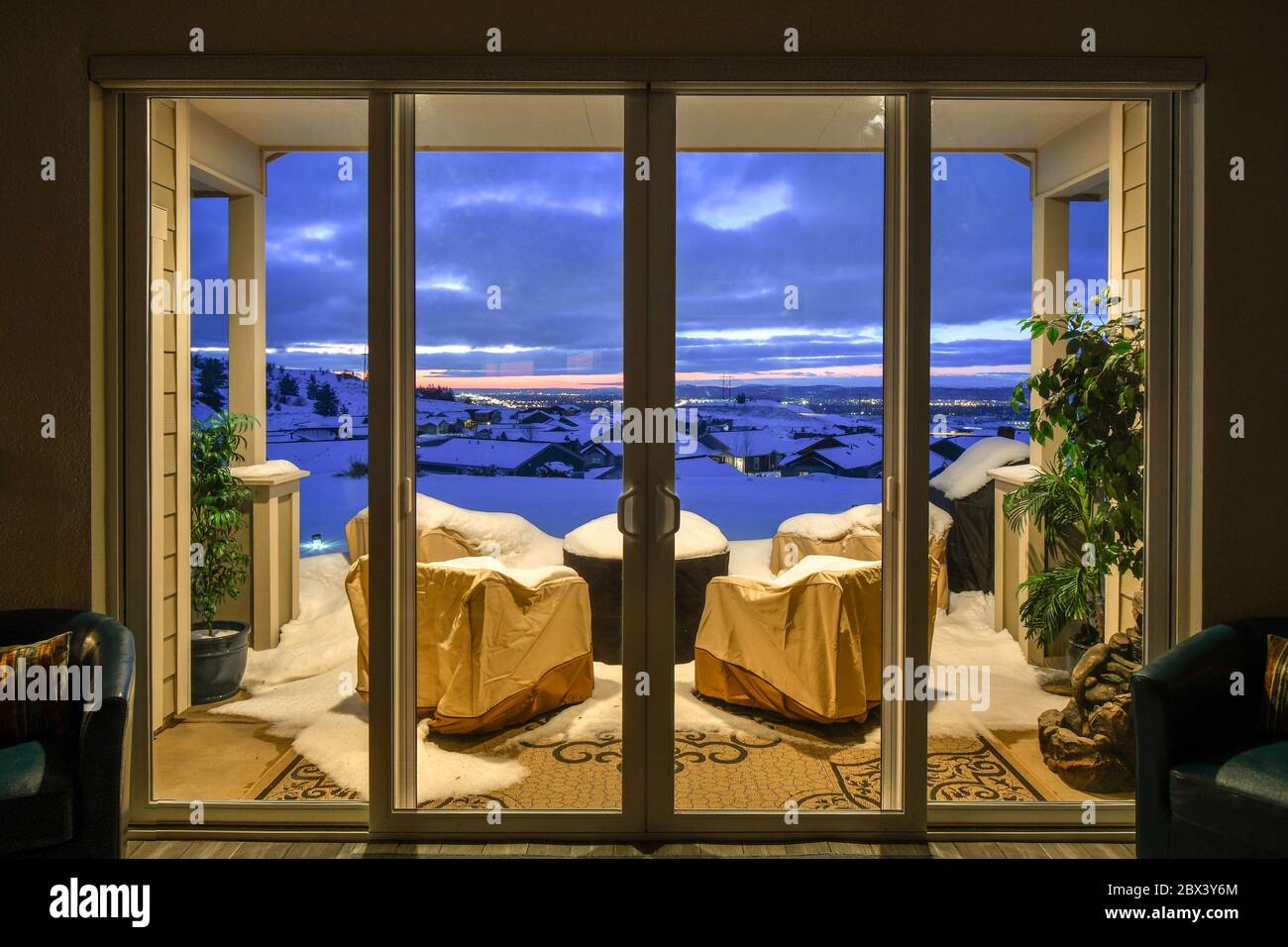 Hillside view from inside looking out to a patio covered in snow with ...