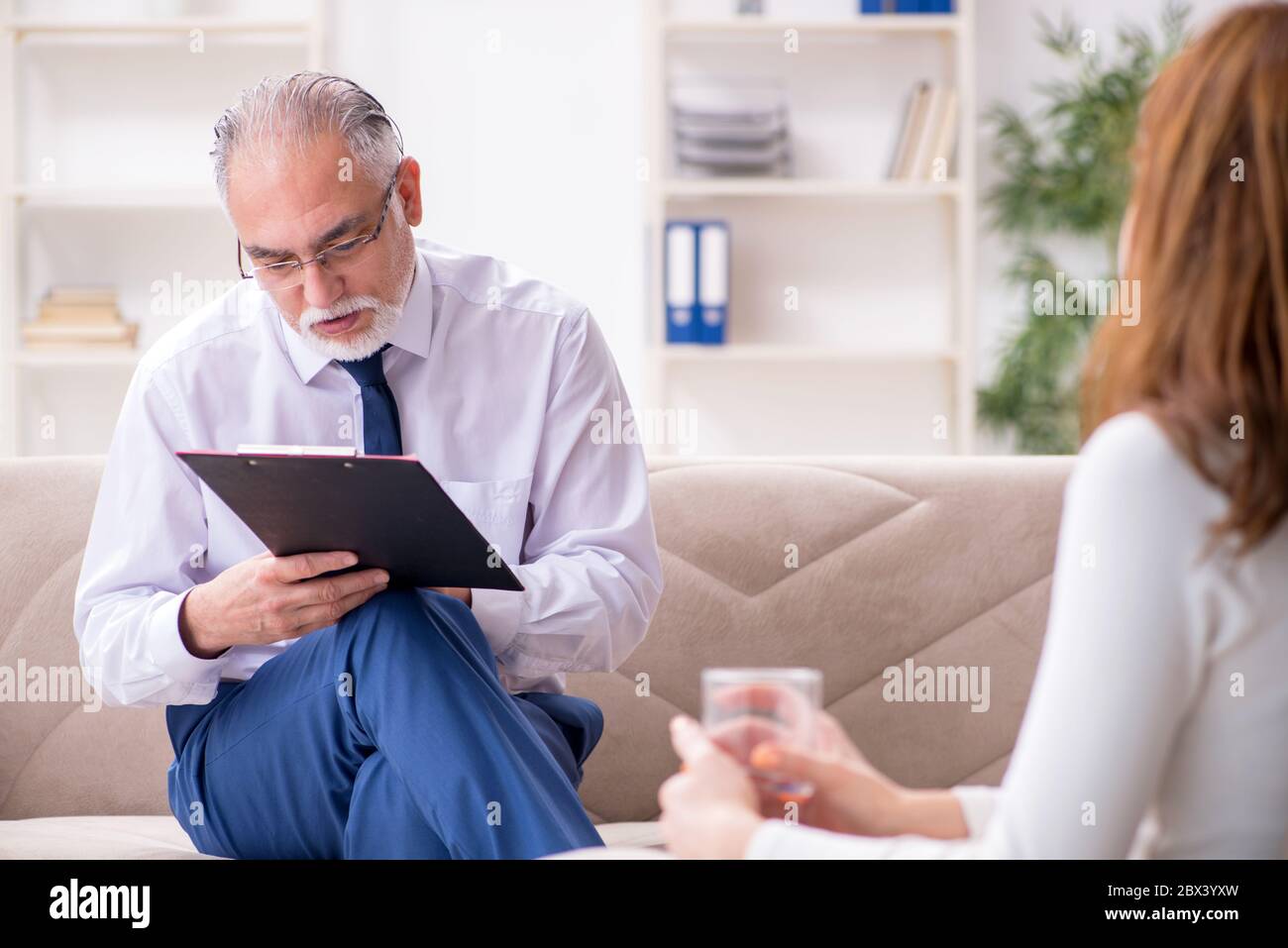Young woman visiting old doctor psychologist Stock Photo - Alamy