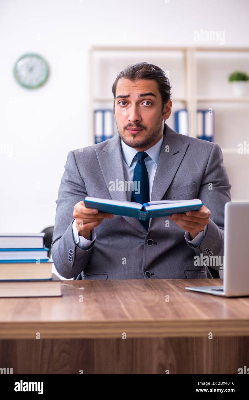 Young businessman reading books at workplace Stock Photo - Alamy