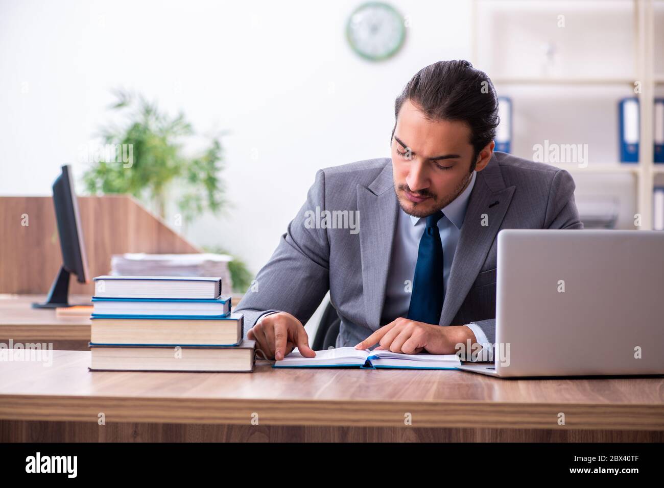 Young businessman reading books at workplace Stock Photo - Alamy