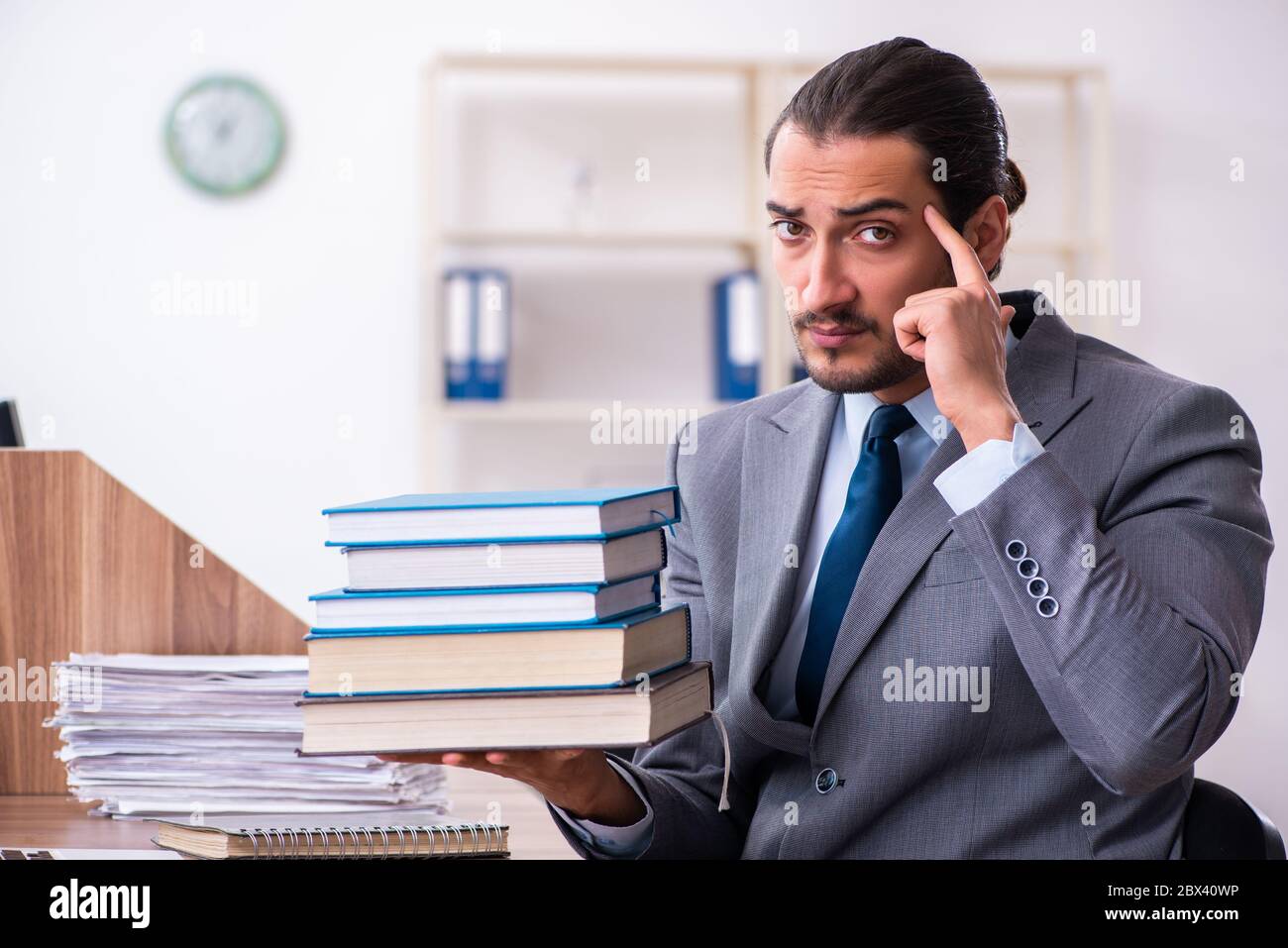Young businessman reading books at workplace Stock Photo - Alamy