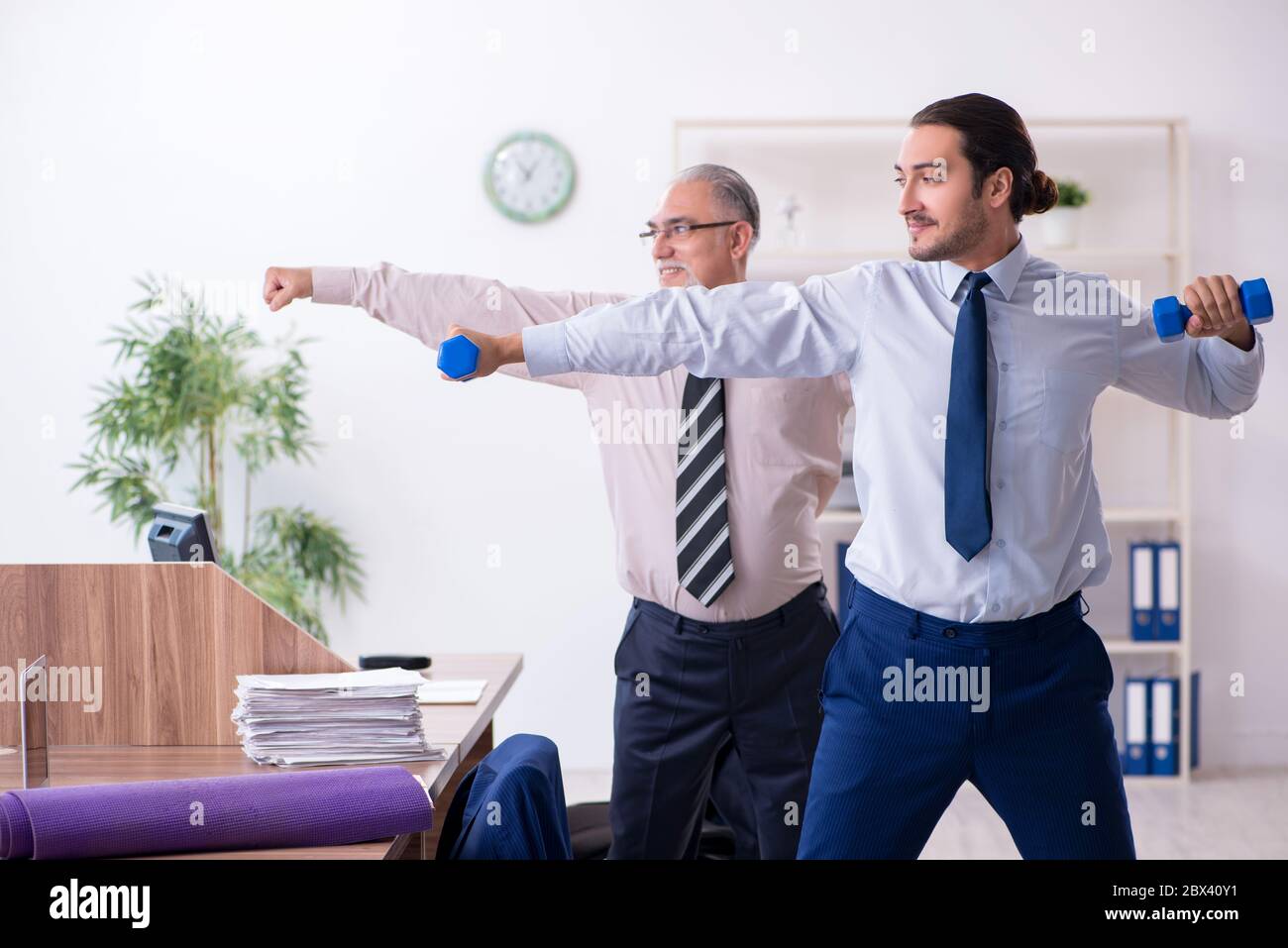Two employees doing physical exercises at the workplace Stock Photo - Alamy