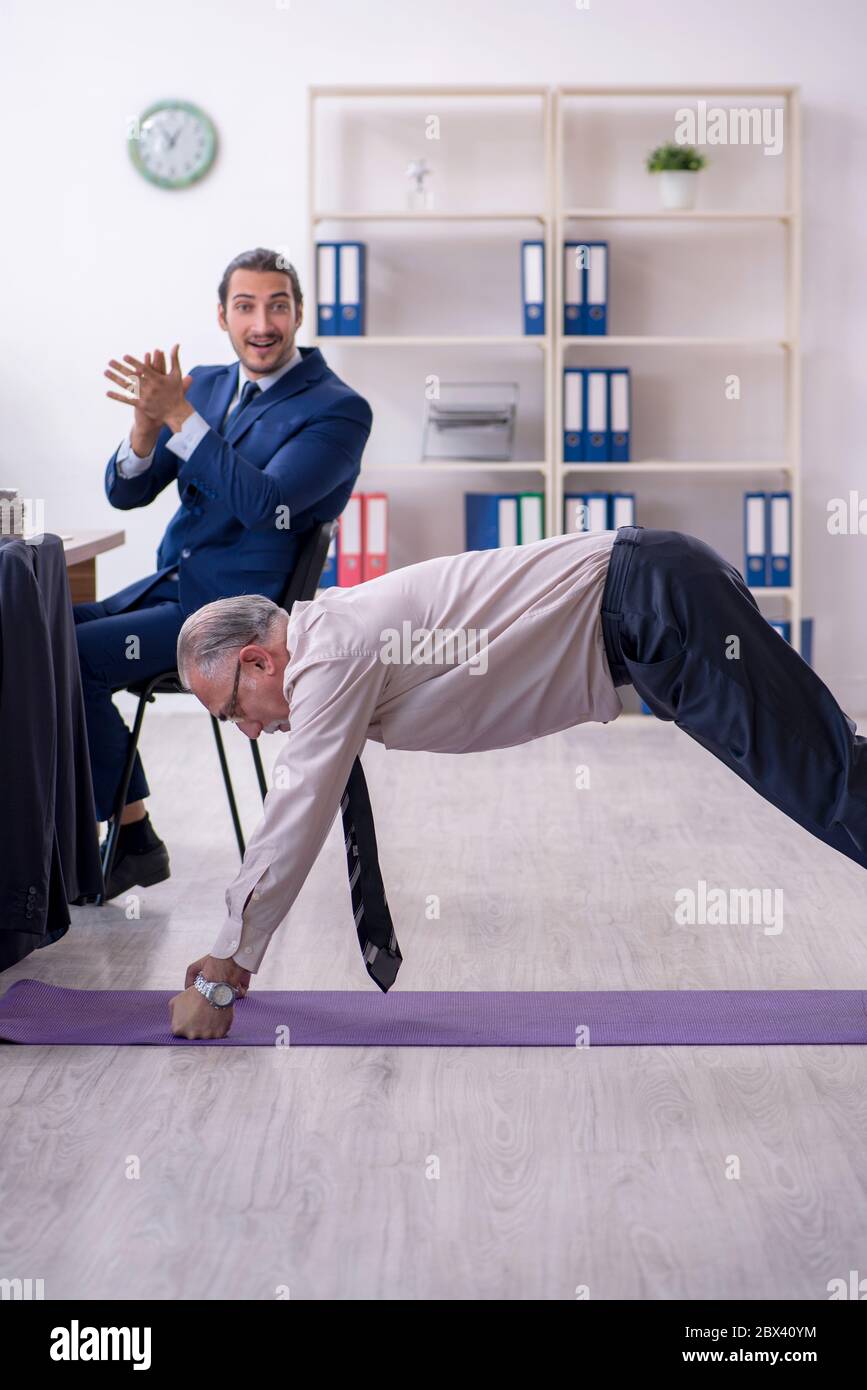Two employees doing physical exercises at the workplace Stock Photo - Alamy