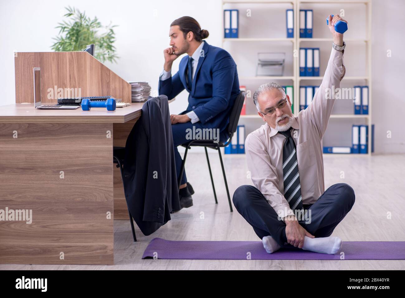 Two employees doing physical exercises at the workplace Stock Photo - Alamy