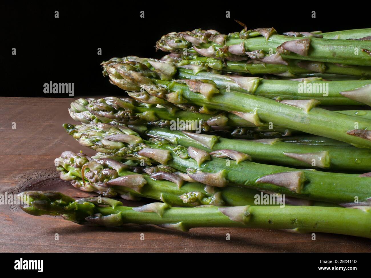 Macro photography of asparagus in a wooden table in black background ...