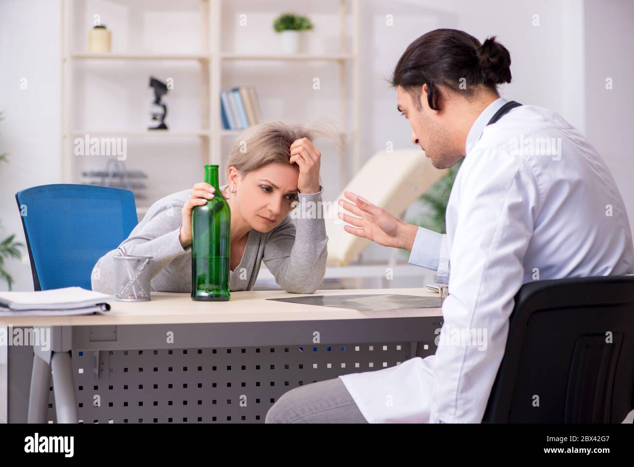 The female alcoholic visiting young male doctor Stock Photo - Alamy