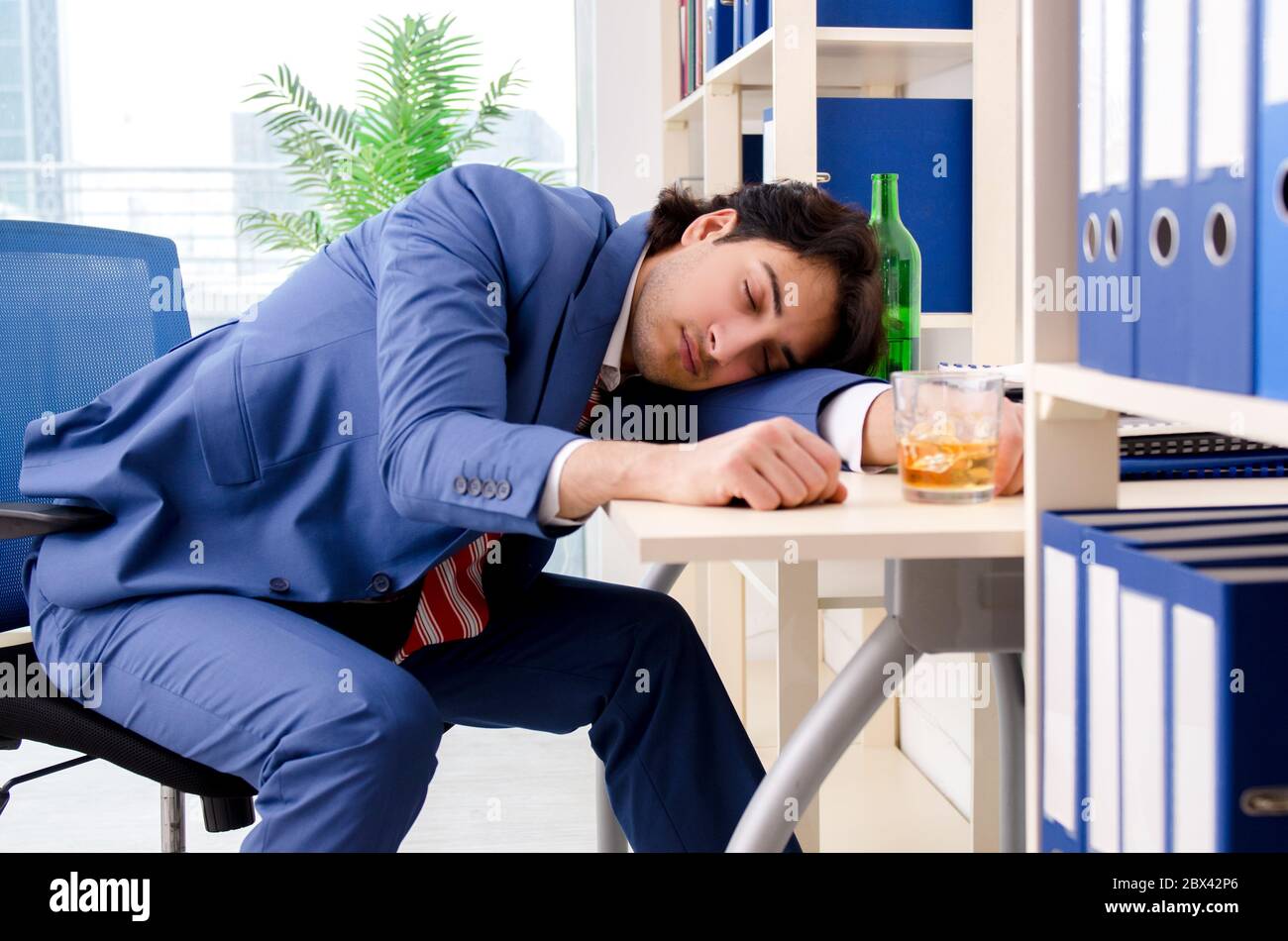 Young businessman employee drinking in office Stock Photo - Alamy