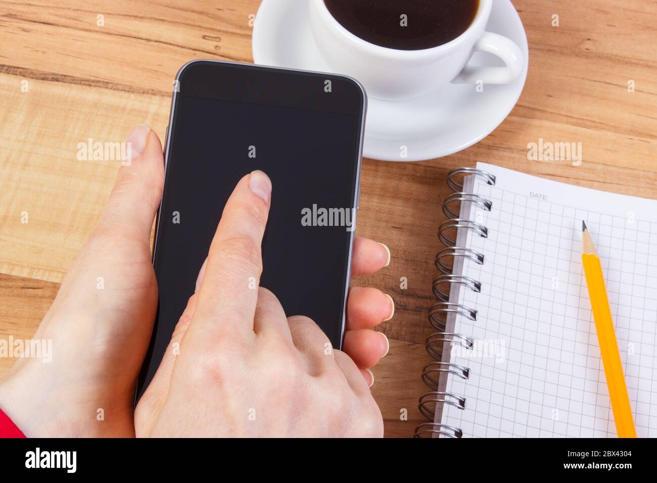 Hand of woman touching blank screen of smart phone, notepad for writing ...