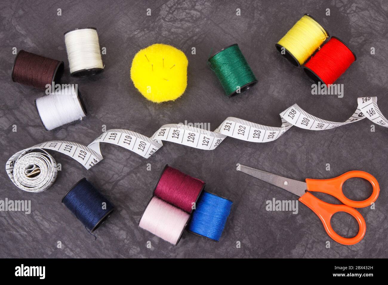Spools of colorful thread, needle, tape measure and scissors ...