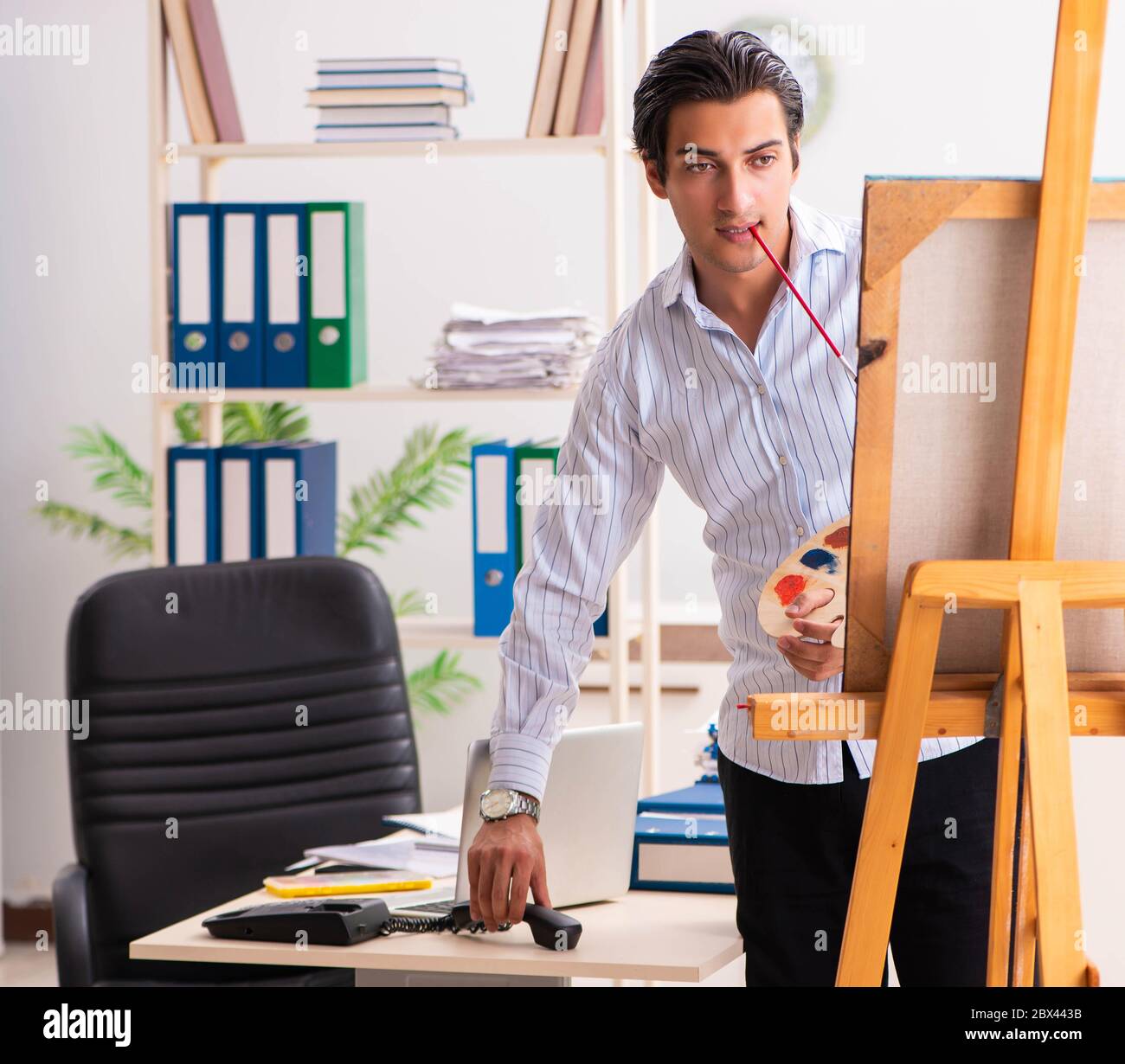 The young handsome employee enjoying painting at the office Stock Photo ...