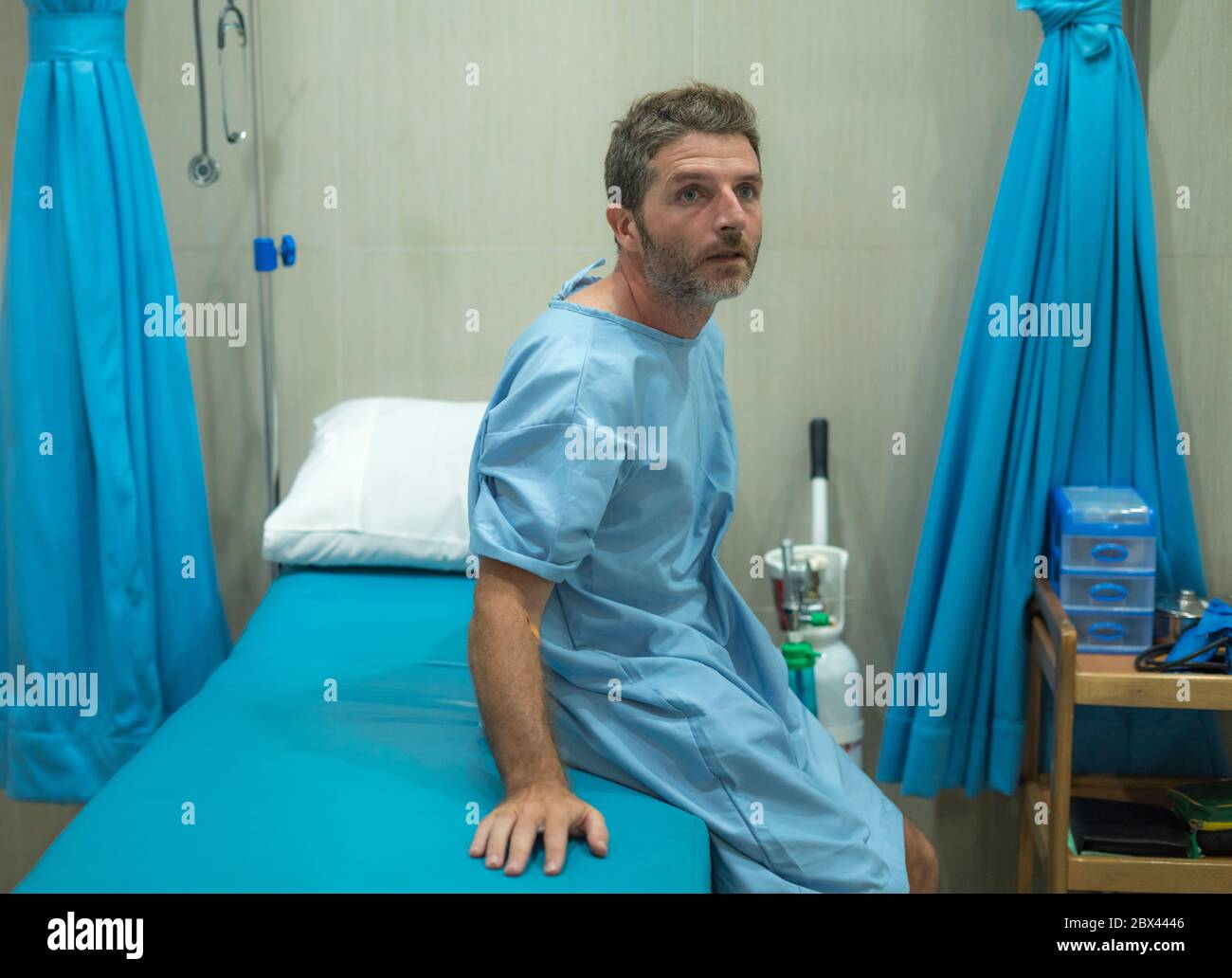scared and worried man hospitalized - attractive injured man sitting on ...